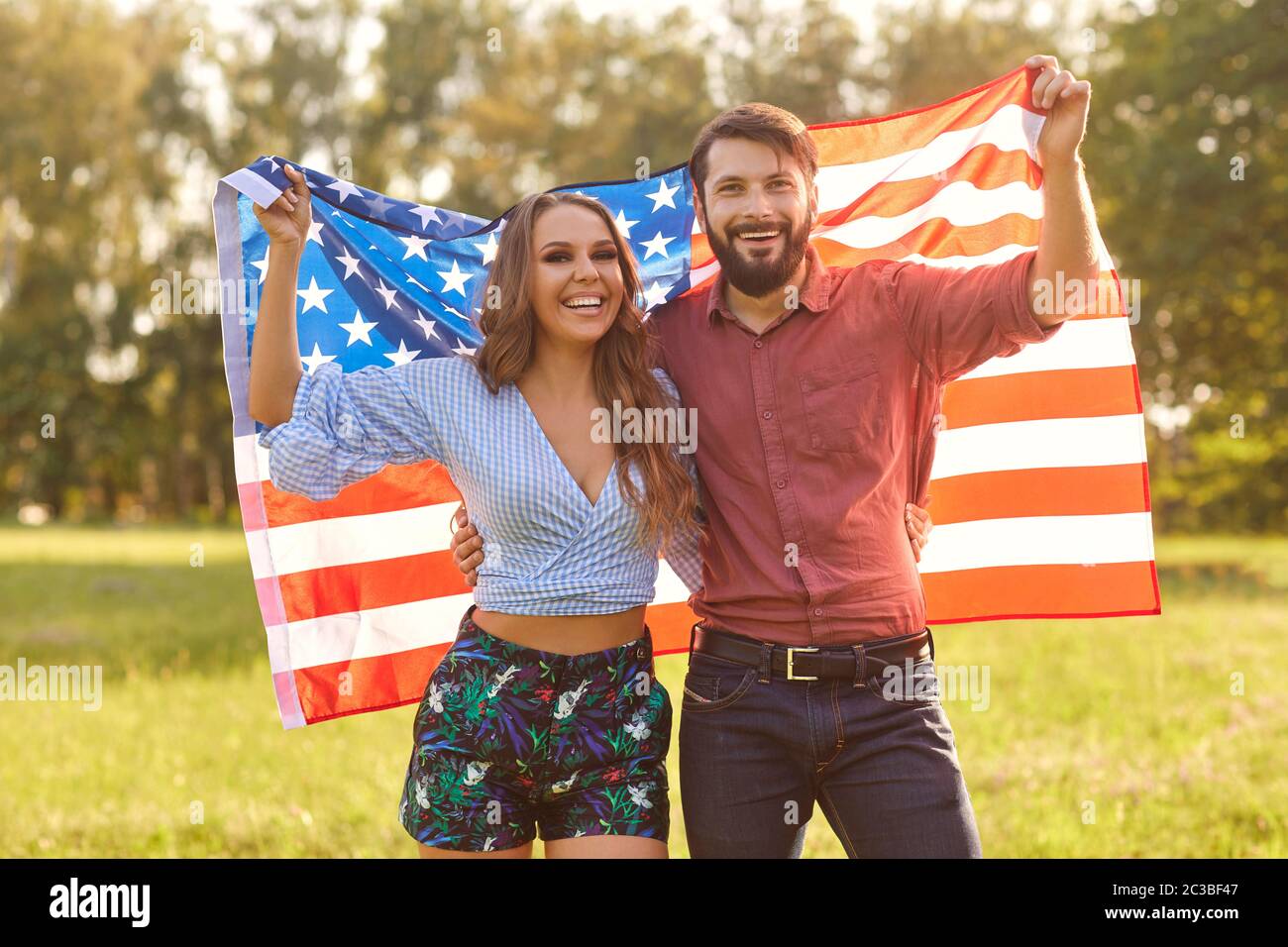 Happy couple with American flag outdoors. Young man and his girlfriend ...