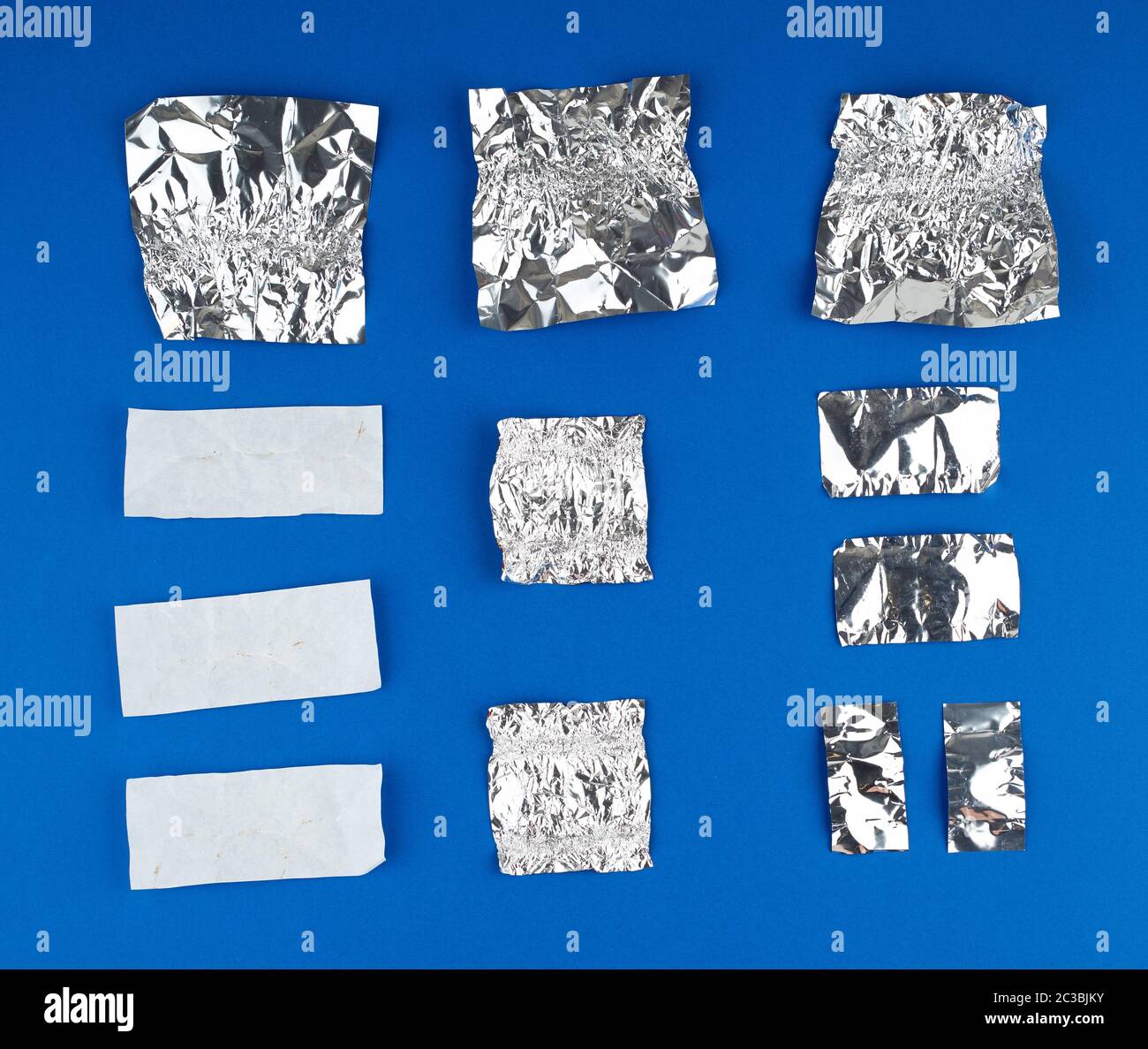 various crumpled white paper and foil used candy wrappers on a blue ...