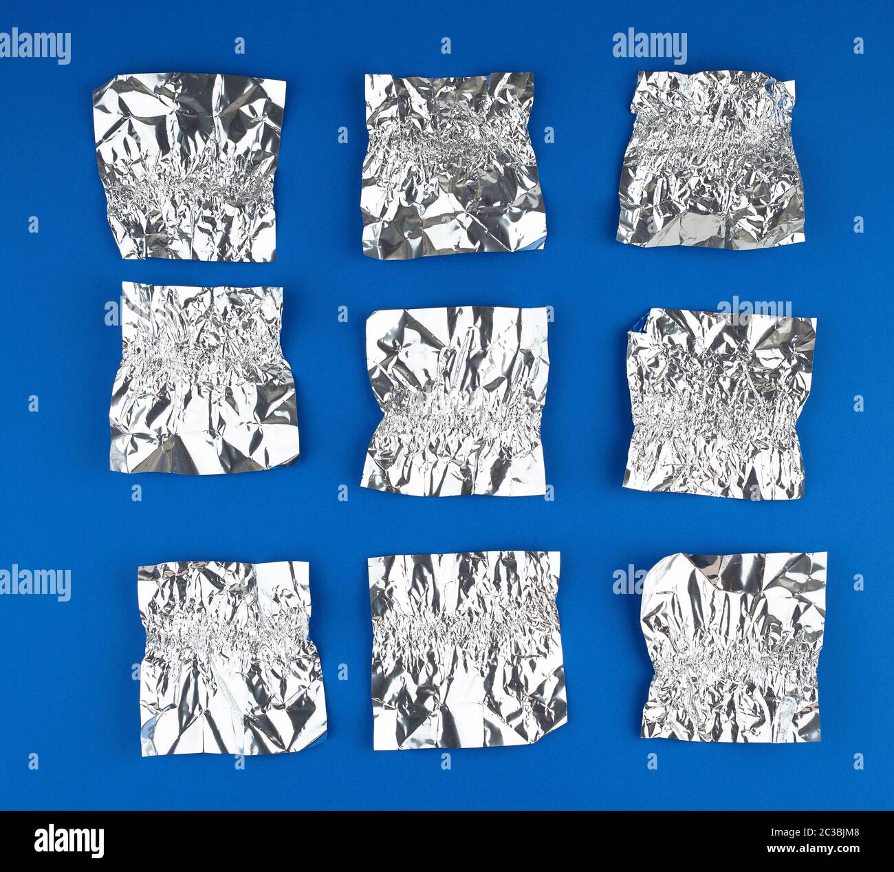 various crumpled foil used candy wrappers on a blue background, top ...