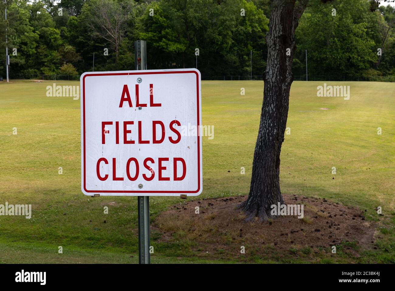 Empty green grass sports field behind a sign saying All Fields Closed ...