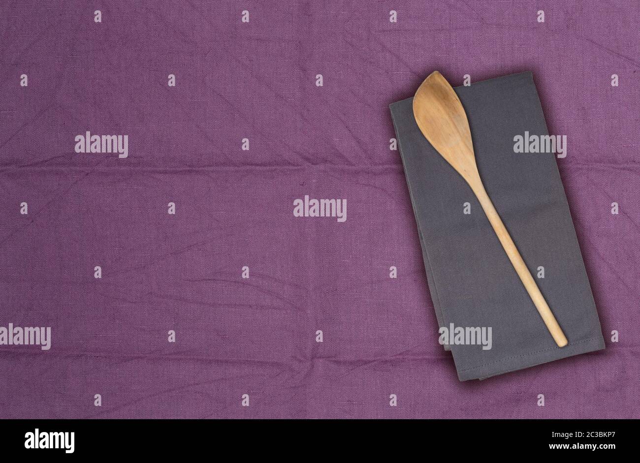 Wooden spoon and kitchen towel on purple fabric Stock Photo - Alamy