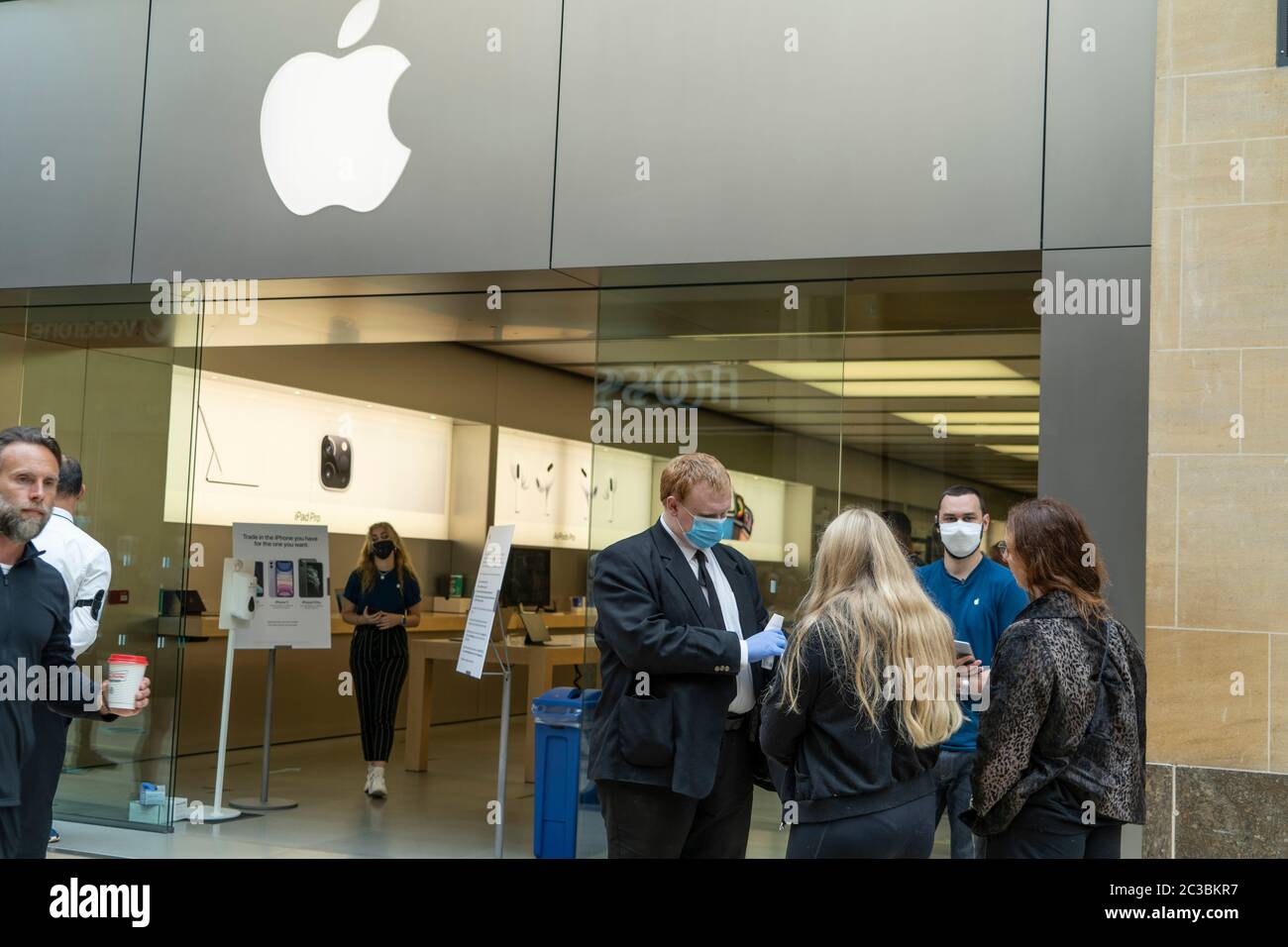 People wear face masks outside the front of the Apple store in ...