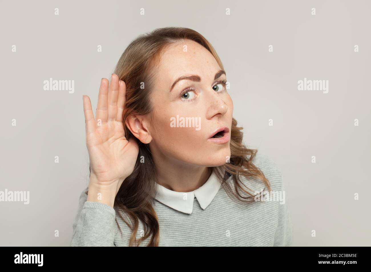 Pretty curious nosy woman listening on white background Stock Photo - Alamy