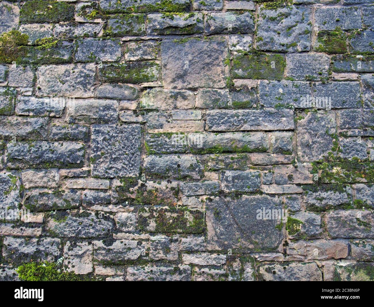 an old grey stone wall made of large irregular blocks covered in ...
