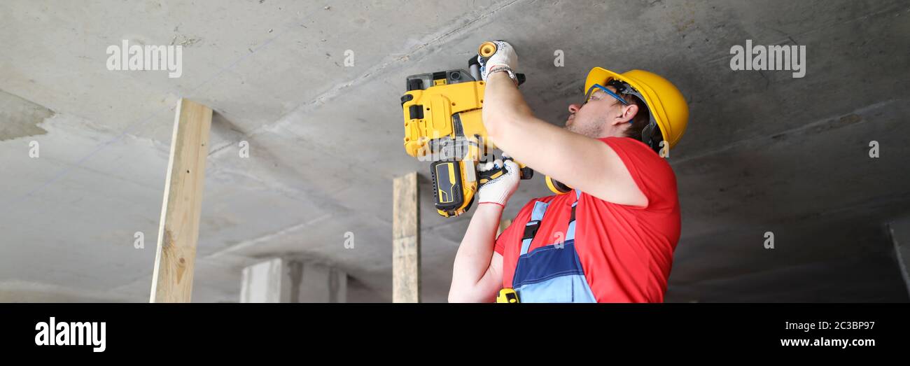 Builder works with special equipment on ceiling Stock Photo - Alamy
