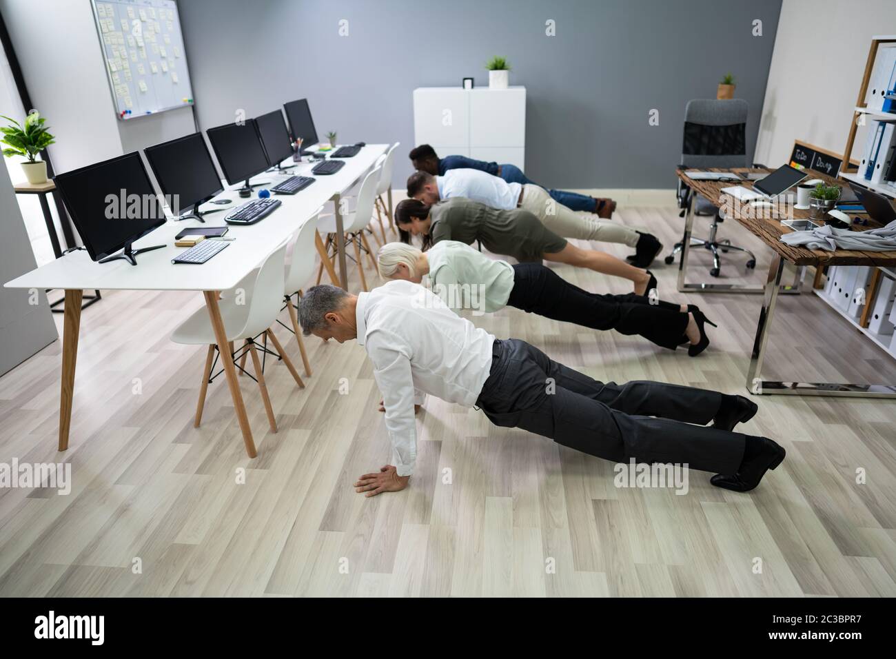 Group Of People Doing Pushups Exercise At Workplace Stock Photo - Alamy