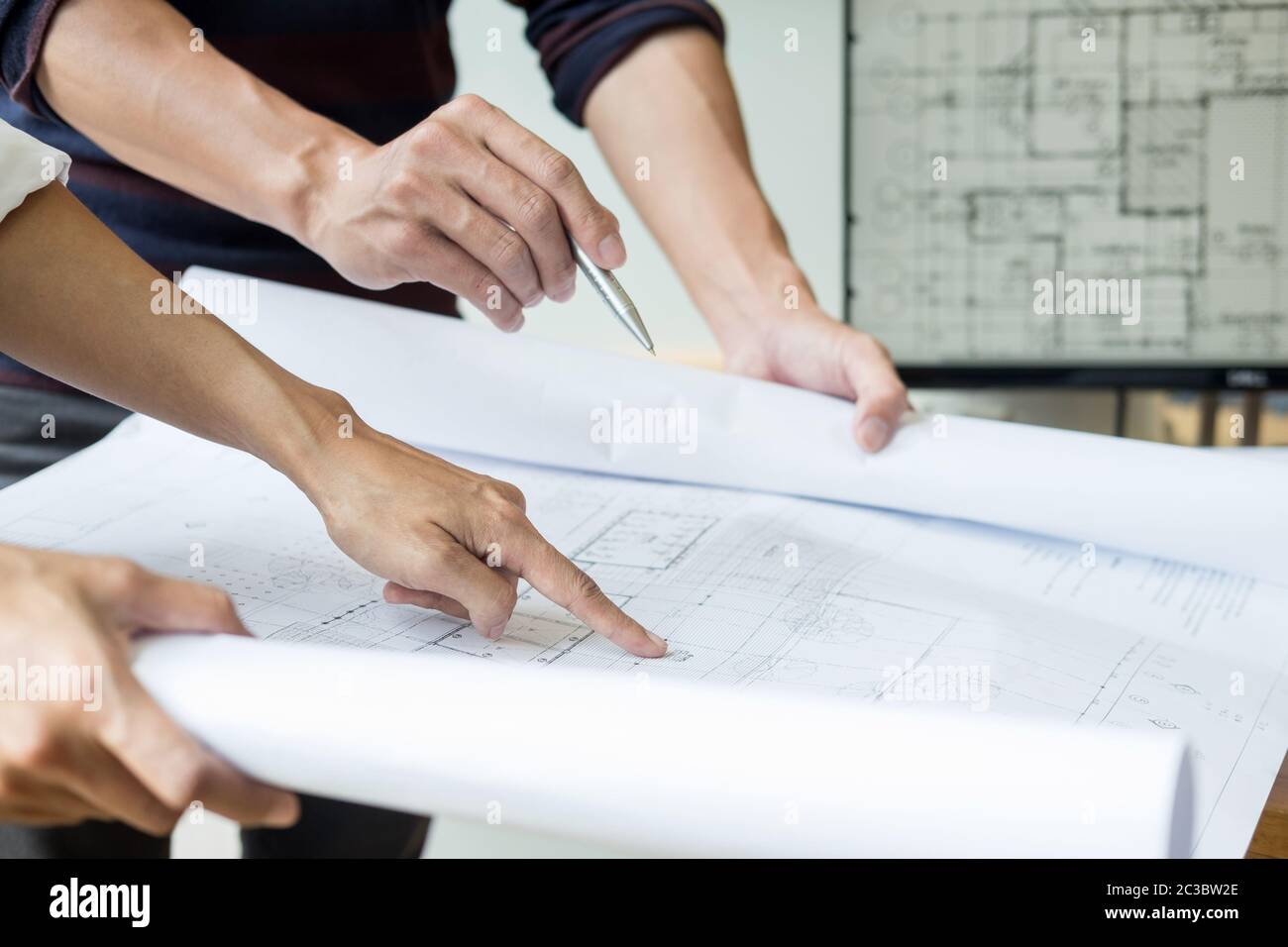 professional architects working on blueprint discussing construction ...