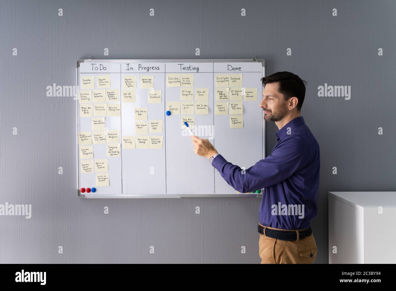 Side View Of Businessman Writing On Sticky Notes Attached To White ...