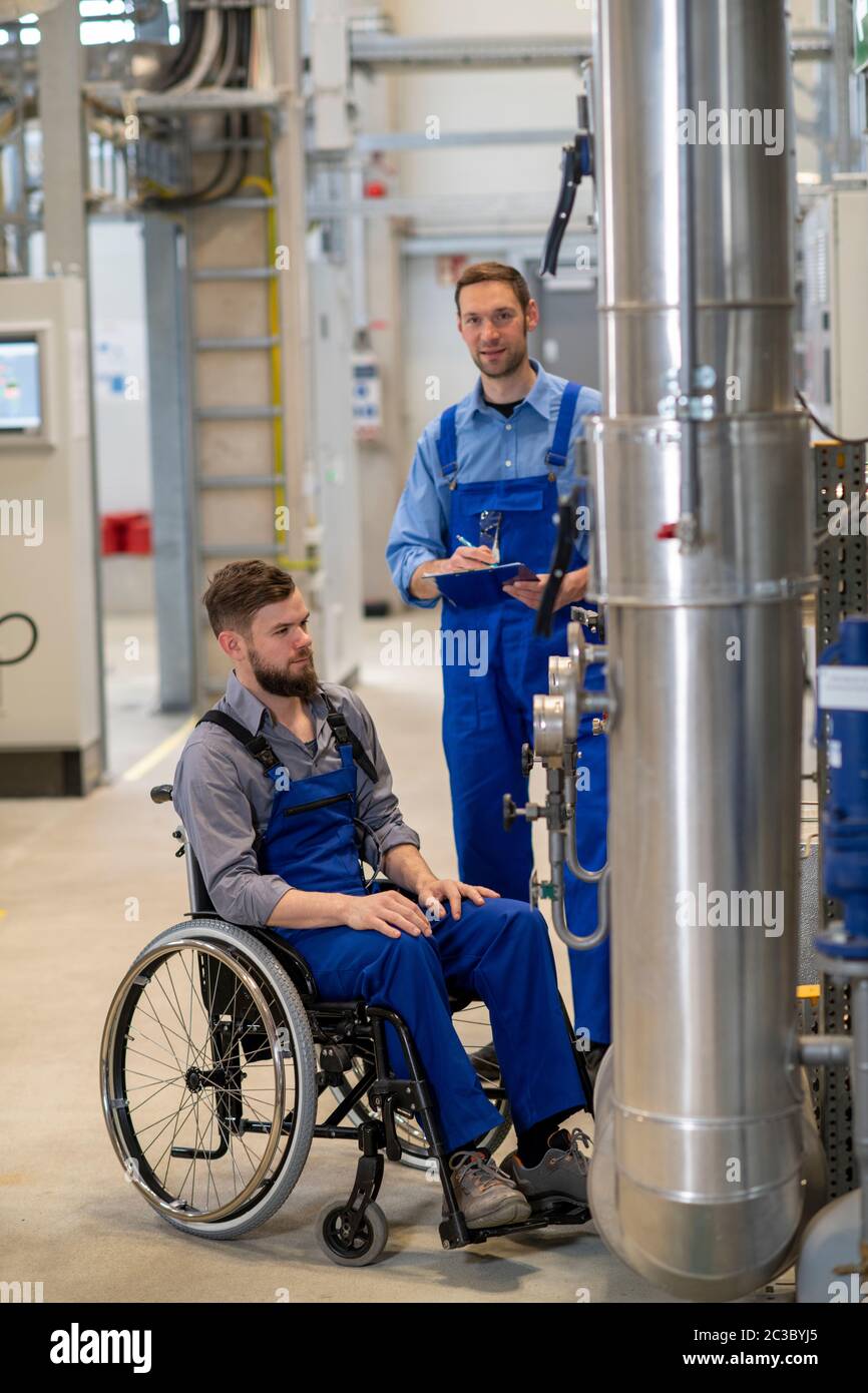 disabled workerwith his colleague in wheelchair in factory Stock Photo ...