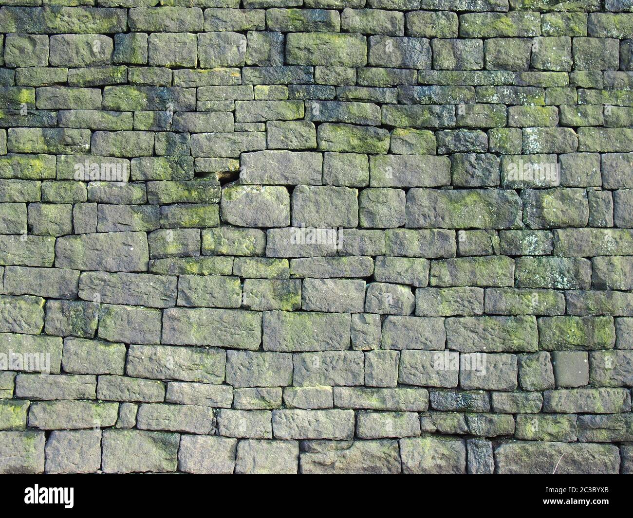 an old grey stone wall made of large irregular blocks covered in ...