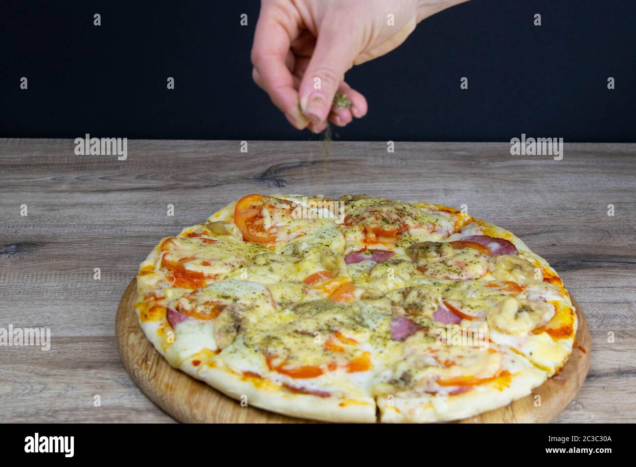 Hand sprinkles ready-made pizza with spices. Delicious hot homemade ...