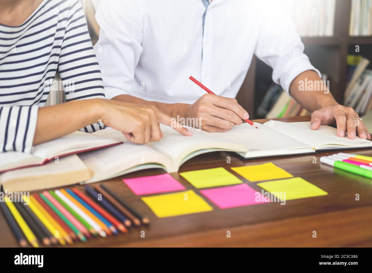 Young students classmates help friend catching up workbook and learning ...