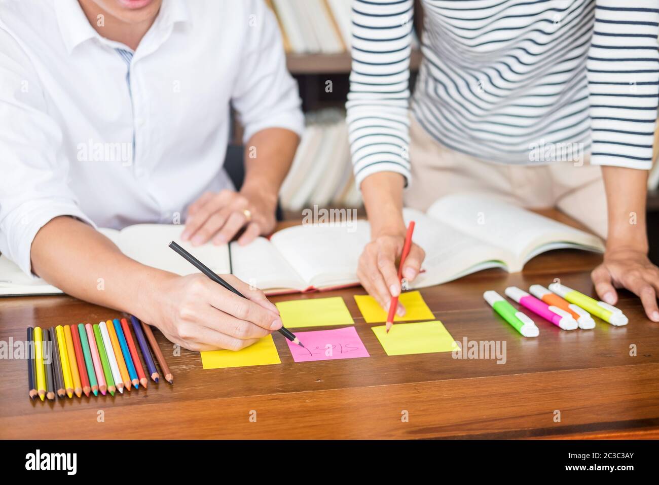 Young students classmates help friend catching up workbook and learning ...