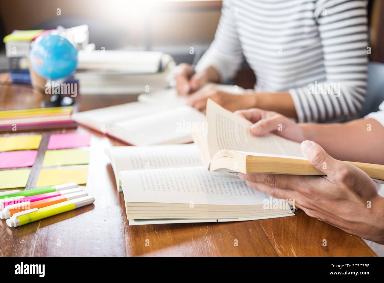Young students classmates help friend catching up workbook and learning ...