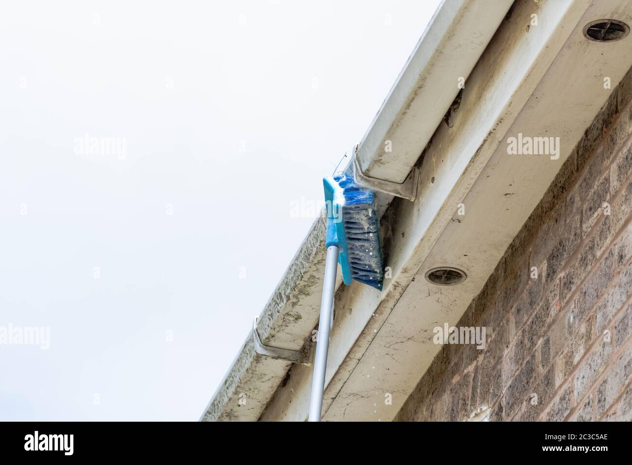 Brushing cobwebs and dust off guttering Stock Photo - Alamy
