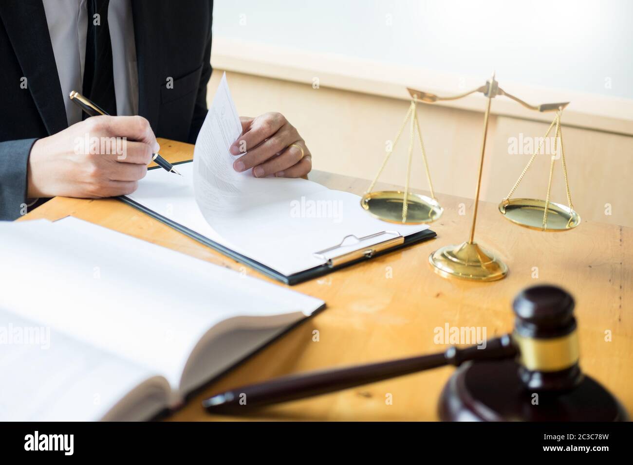 Male lawyer working with contract papers and reading law book in a ...