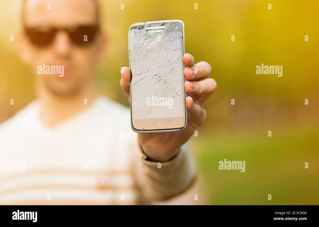 guy holding black smartphone with broken display. Broken screen of ...