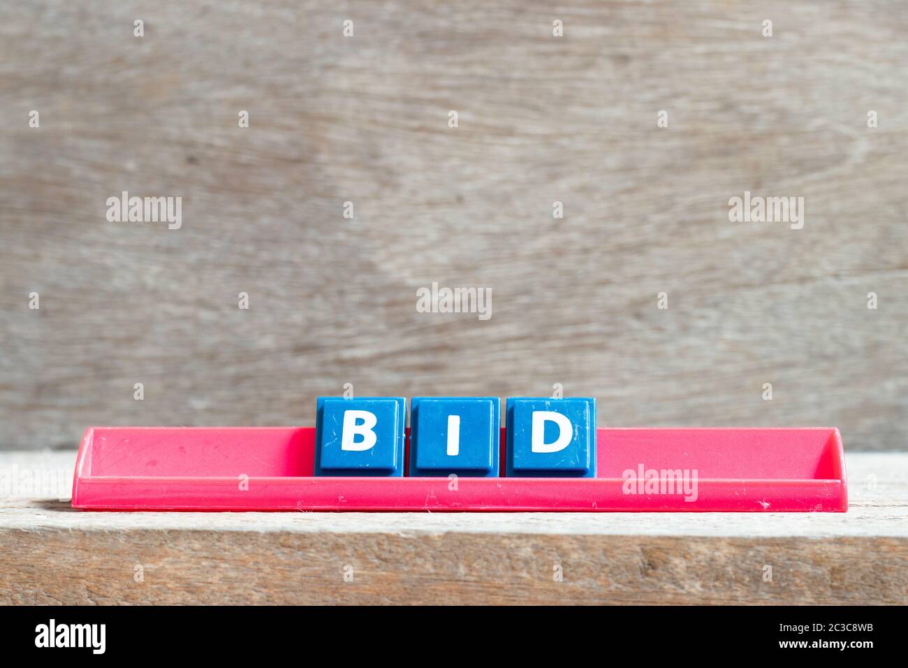 Tile letter on red rack in word bid on wood background Stock Photo - Alamy