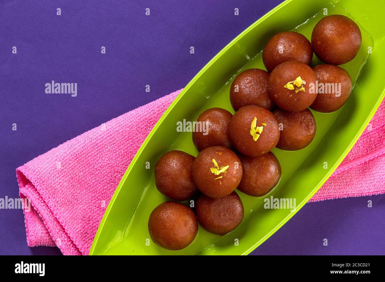 Indian Dessert Gulab Jamun in plate on purple background with napkin ...