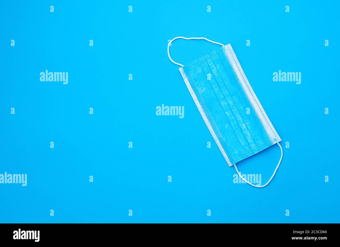 blue sterile medical mask with white elastic bands for doctors on a ...
