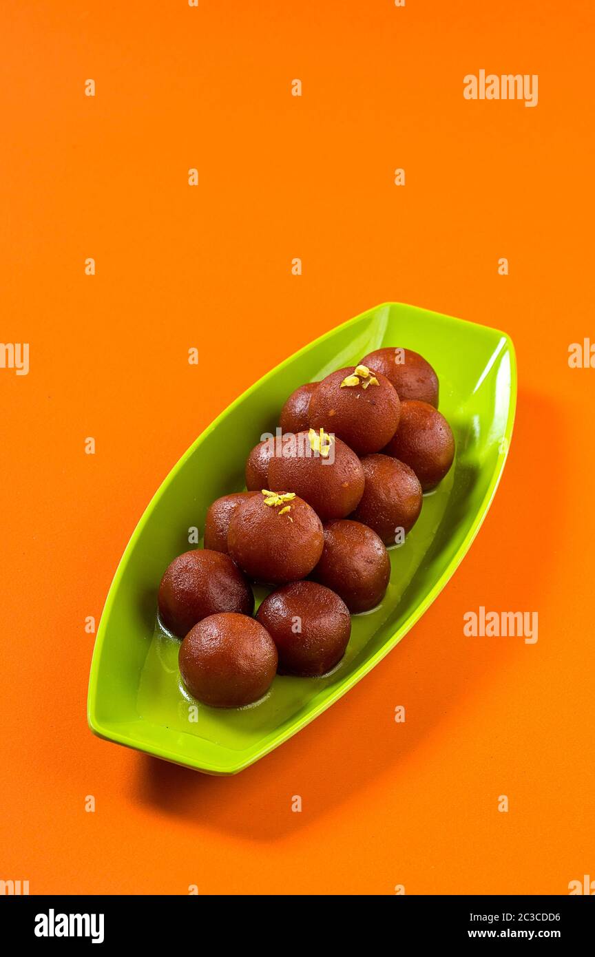 Indian Dessert Gulab Jamun in plate on orange background Stock Photo ...