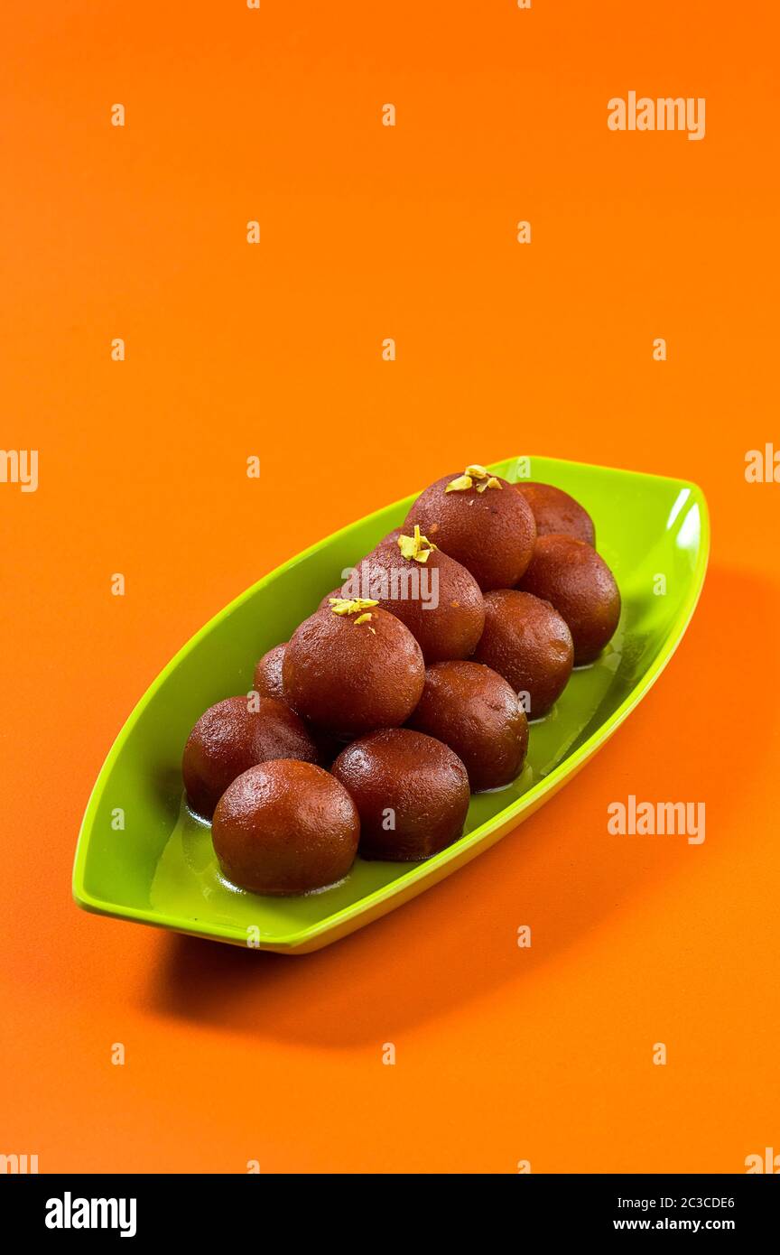 Indian Dessert Gulab Jamun in plate on orange background Stock Photo ...