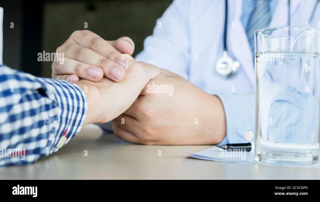 male doctor holding patient's hand, comforting patient who is in ...