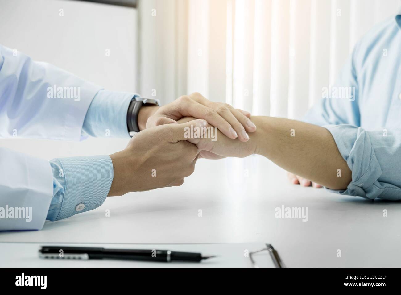 male doctor holding patient's hand, comforting patient who is in ...