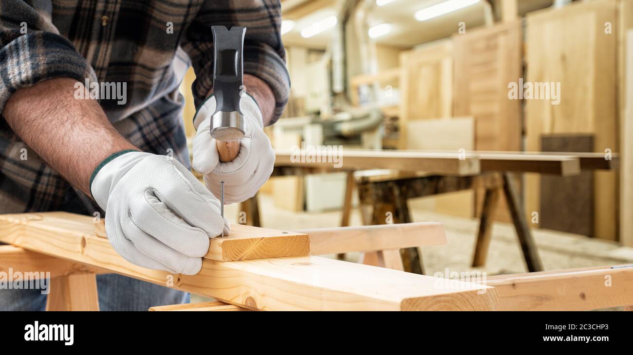 Close-up. Carpenter with his hands protected by gloves with hammer and ...