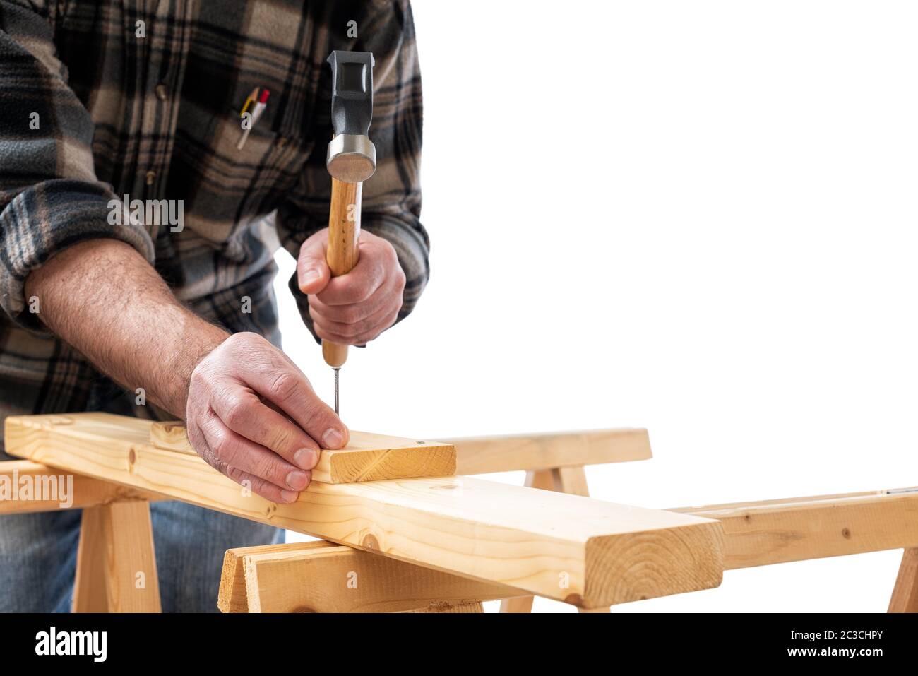 Close-up. Carpenter with hammer and nails fixes a wooden board ...