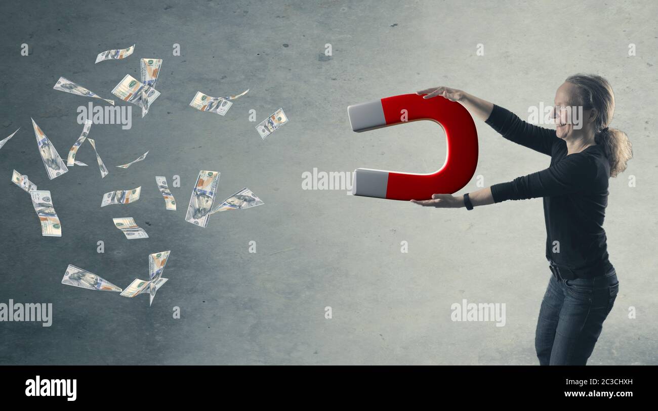 Happy woman with a big magnet attracting money Stock Photo - Alamy