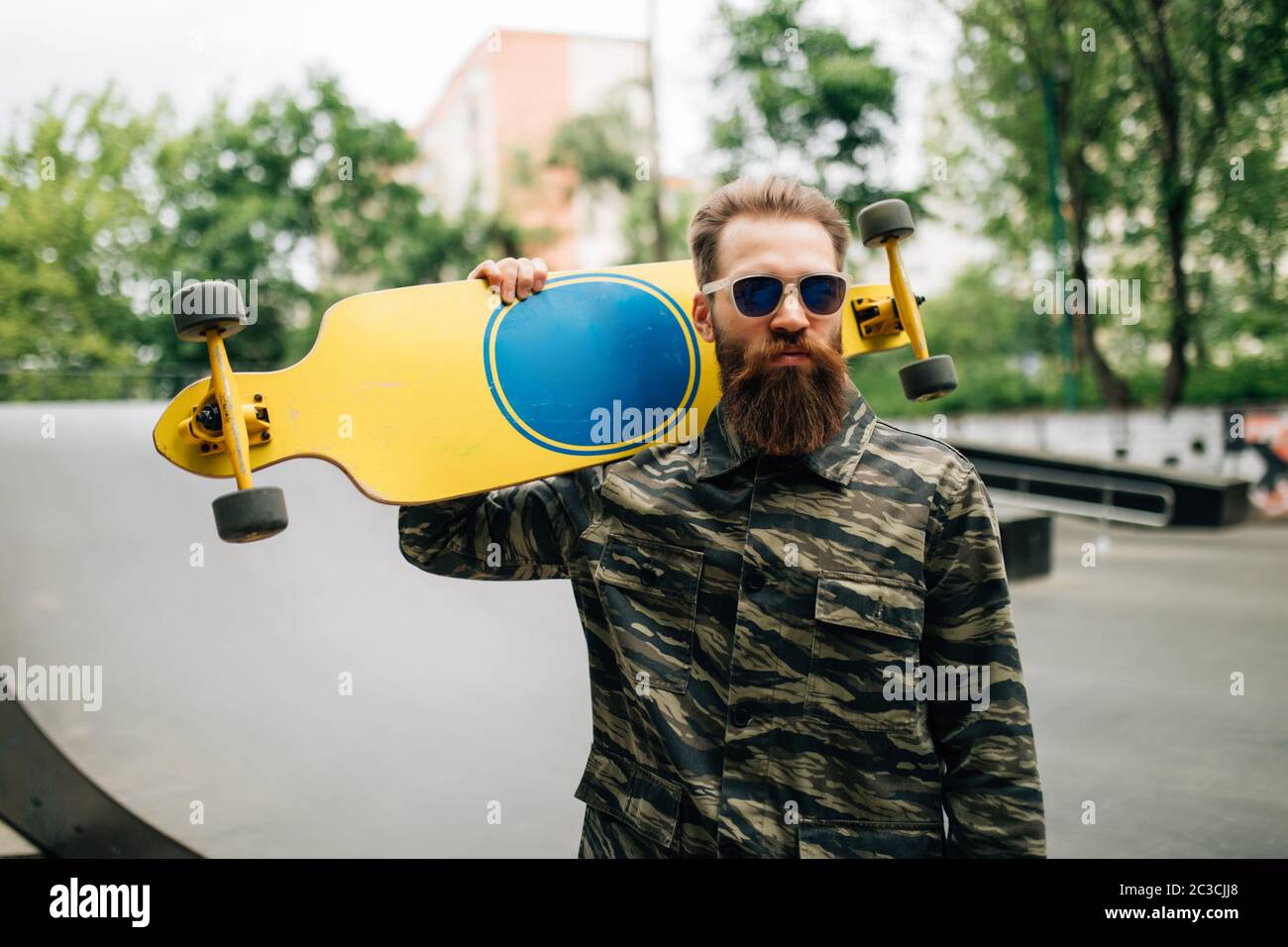 Urban guy lifestyle. Smiling bearded man with skateboard in extreme ...