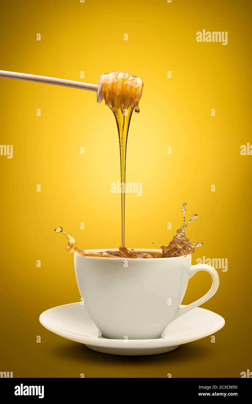 Honey dripping into cup of tea, on yellow background Stock Photo - Alamy