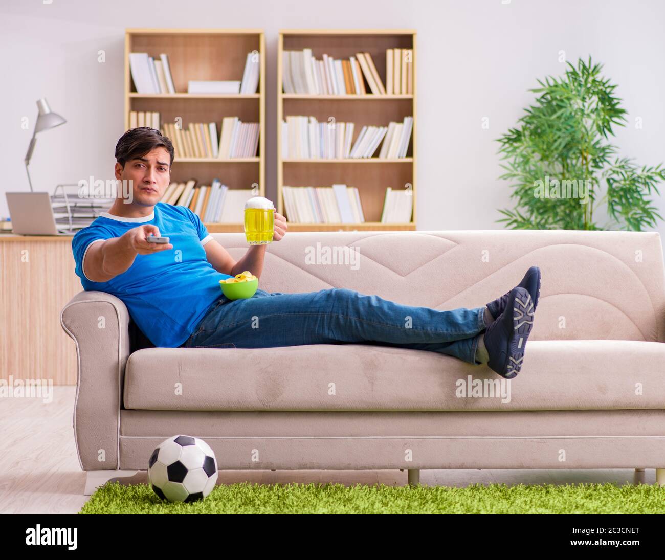 Man watching football at home sitting in couch Stock Photo - Alamy