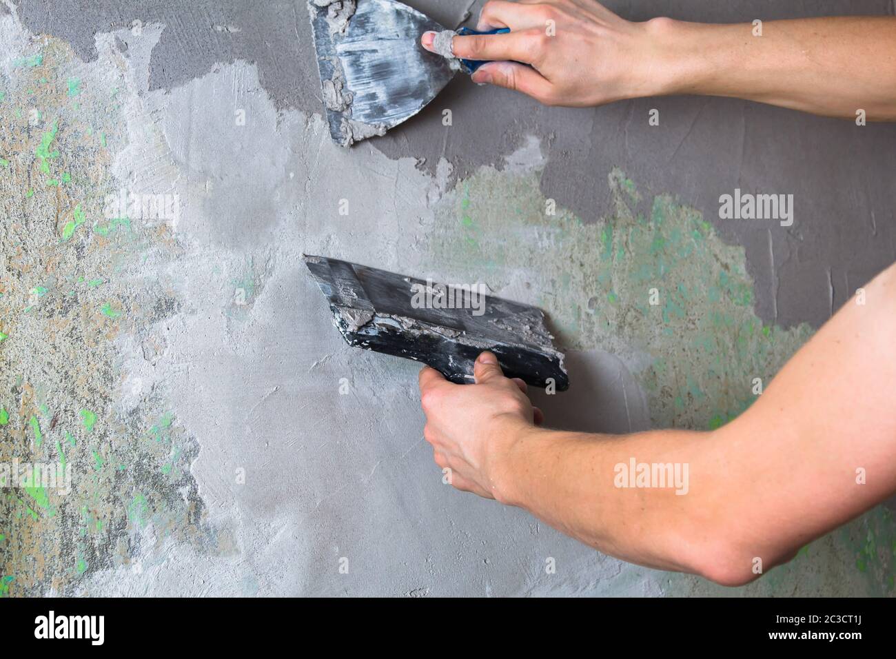 Hand holding a spatula with construction mix and smoothes out bumps ...