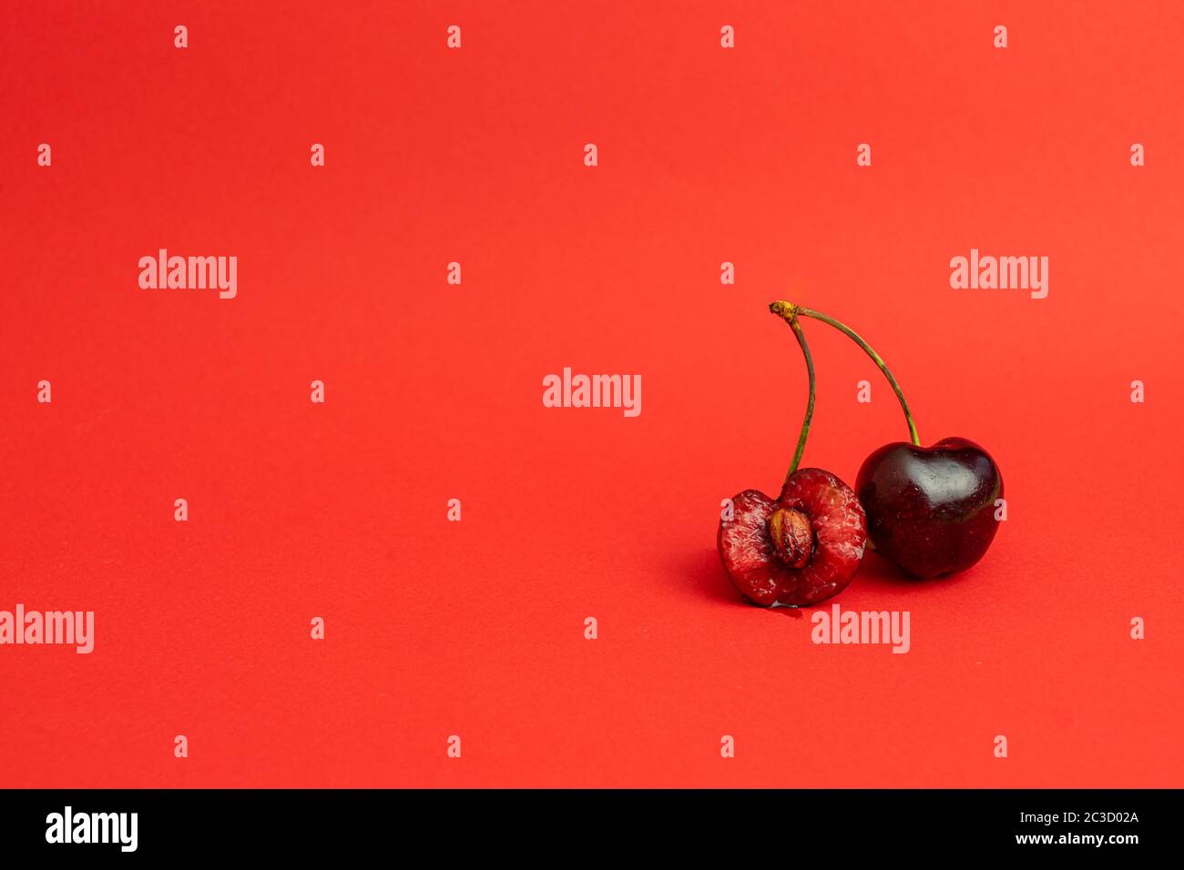 Two cherries on the right on a deep red background. Bitten cherry with ...