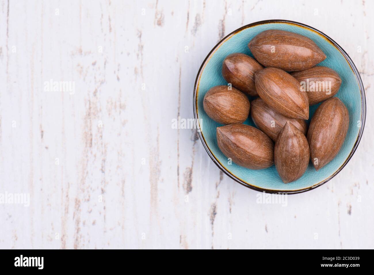 Pecan nuts with the nutshell on a white textured background, empty copy ...