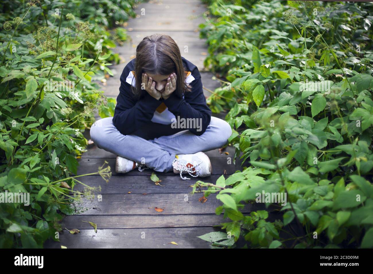 Sad girl sitting in garden Stock Photo - Alamy