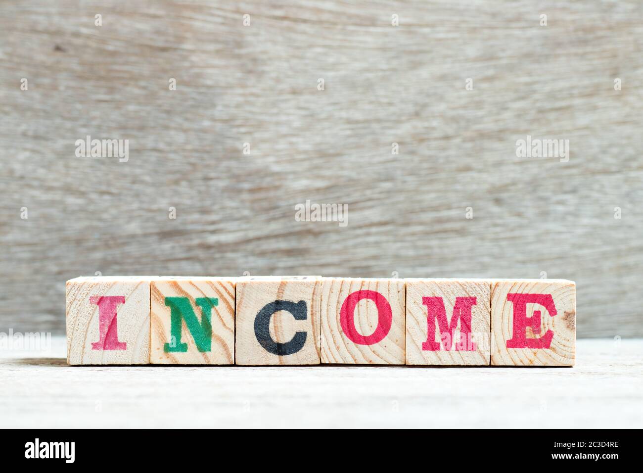 Letter block in word income on wood background Stock Photo - Alamy