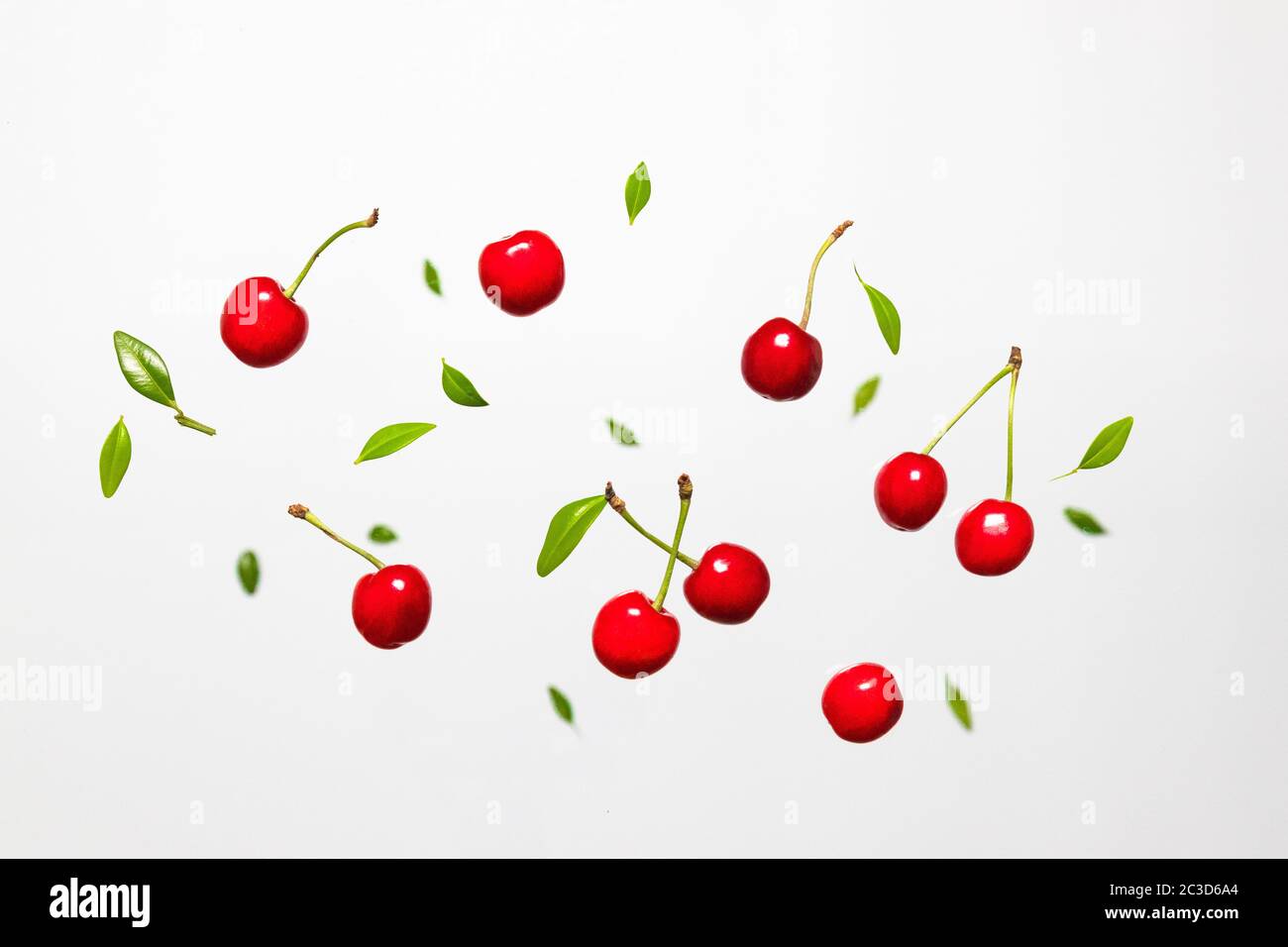 Falling fresh ripe cherries with green leaves isolated on white ...