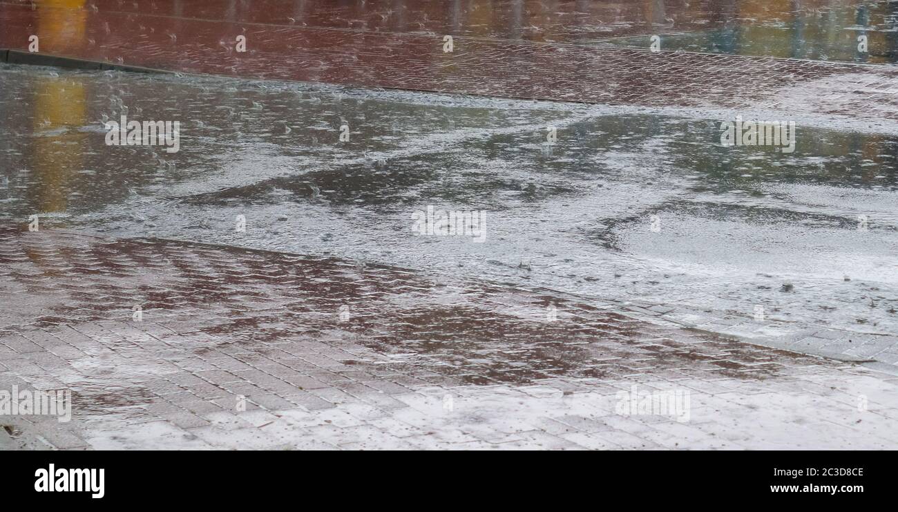 Heavy rain drops falling on city street during downpour. Wet ashpalt ...