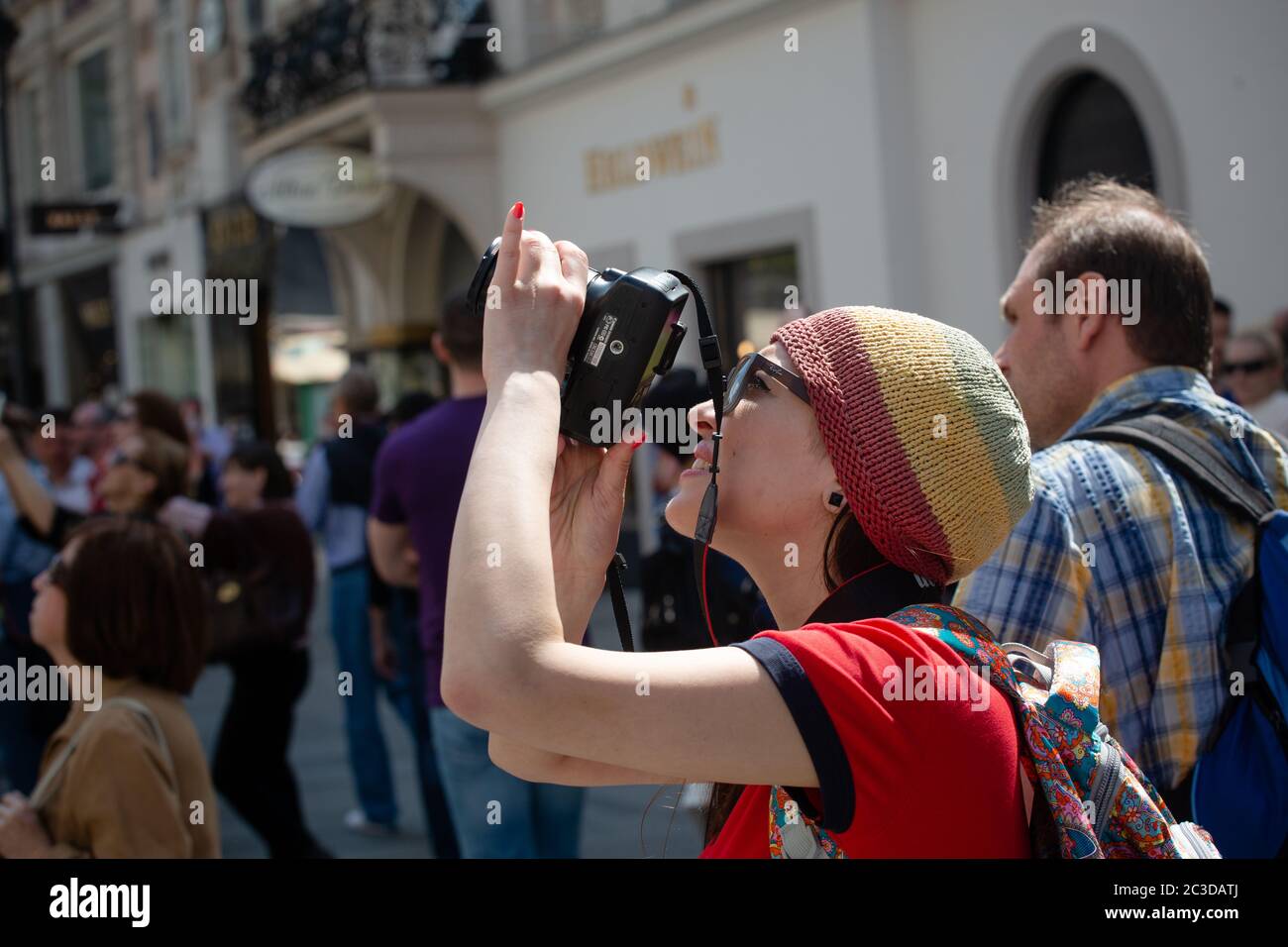 Female tourist makes photo of attractions on the street among the crowd ...