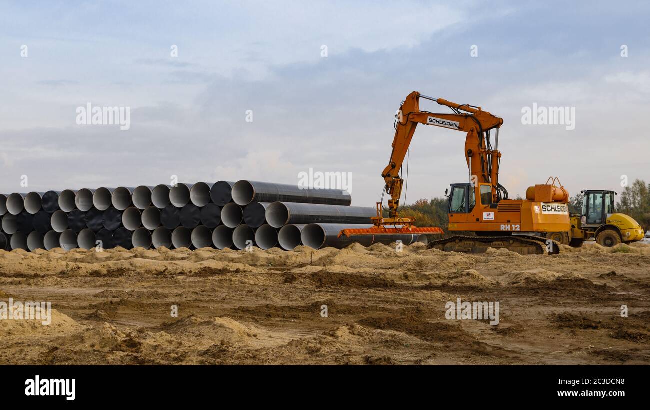 Stack of 8-m-sections of gas pipeline tubes next to a working site. A ...