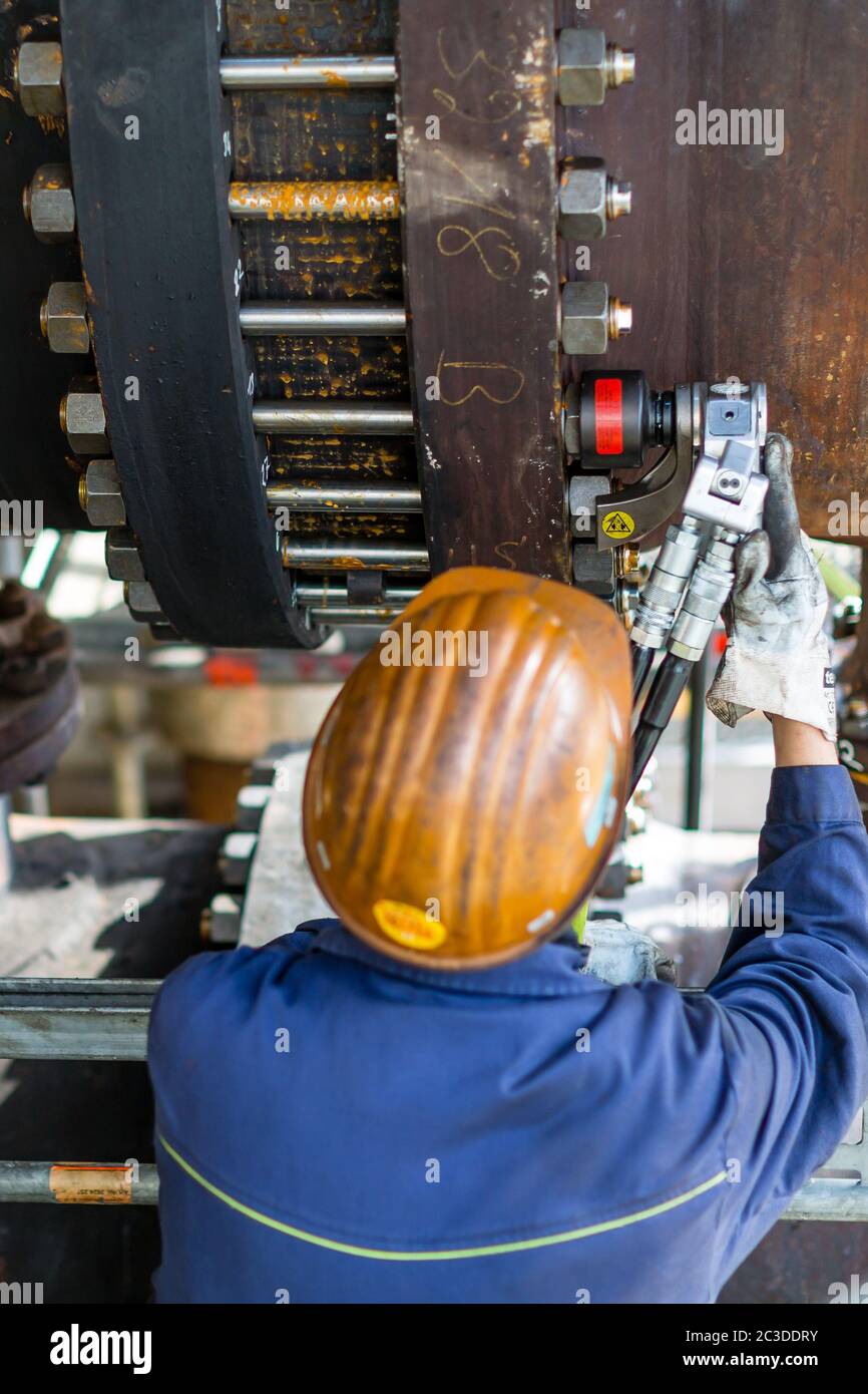 A mechanic with Personal Protective Equipement, seen from behind, is ...