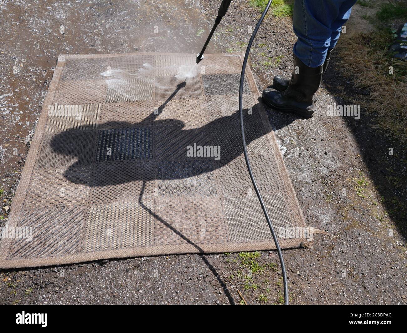 Pressure washing a carpet outside, silhouette of man in boots , done in ...