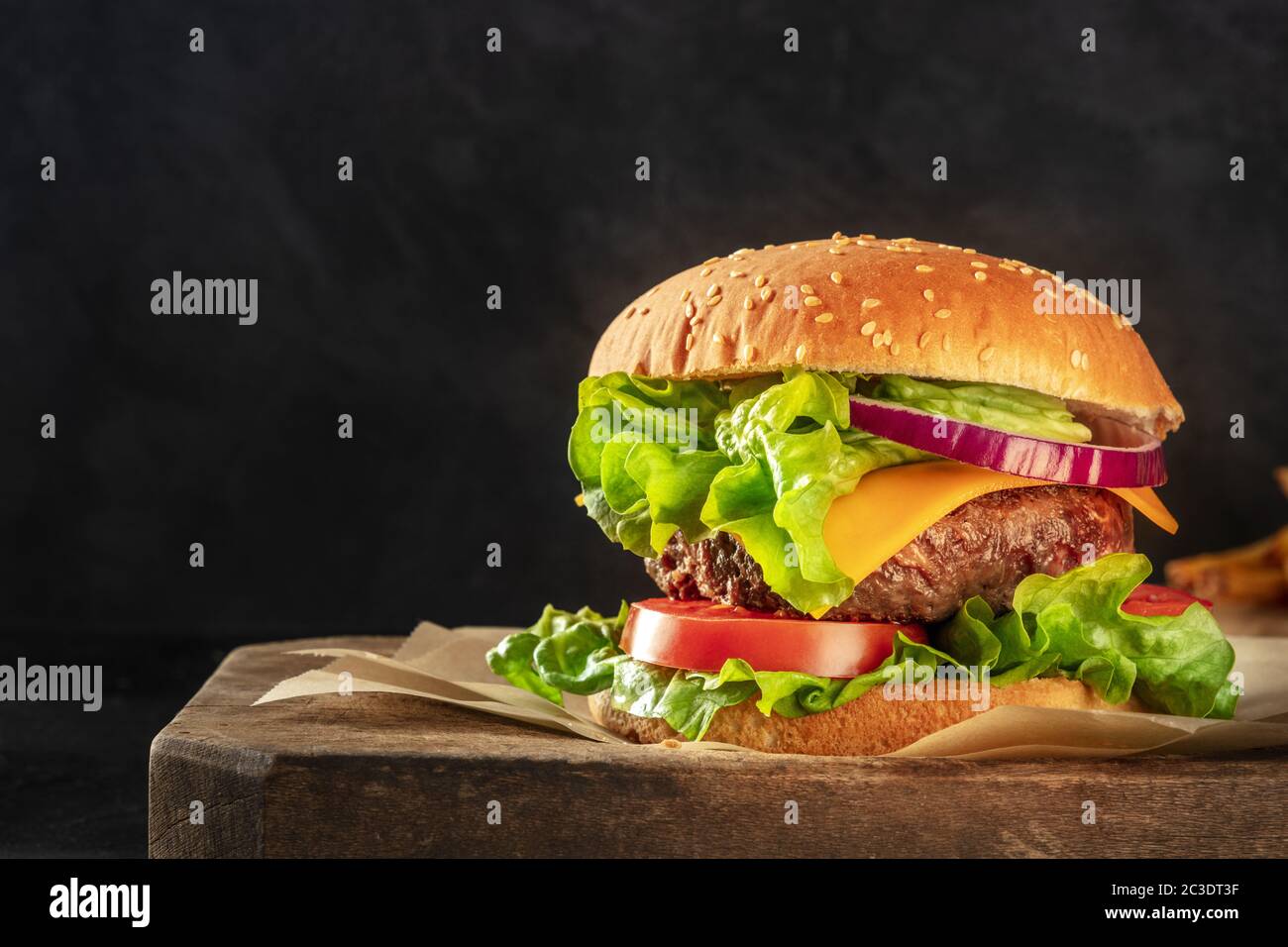 Burger with beef, cheese, onion, tomato, and green salad, a side view ...