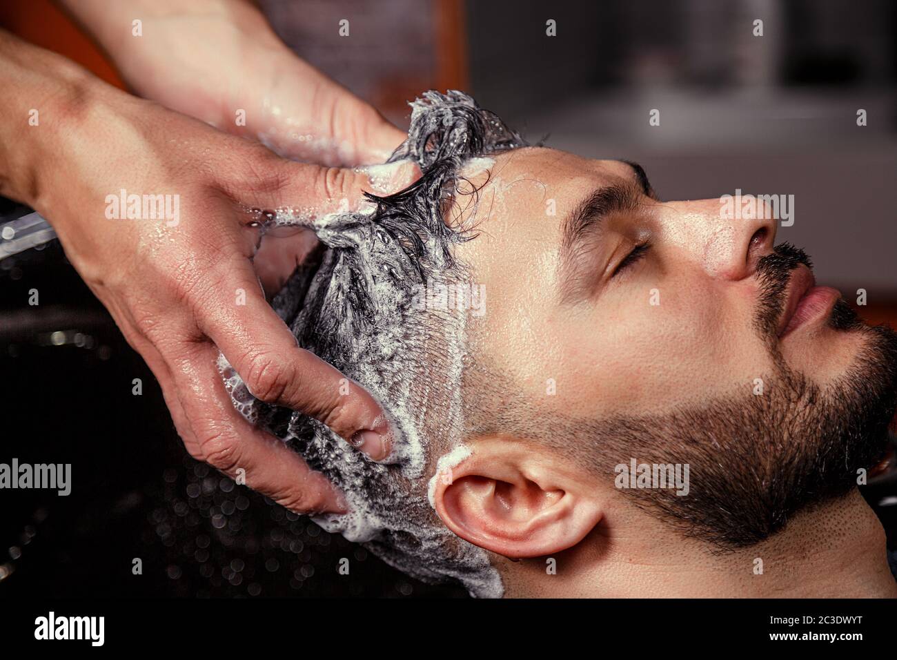 a young dark-haired guy of Indian or Asian appearance in a Barber shop ...