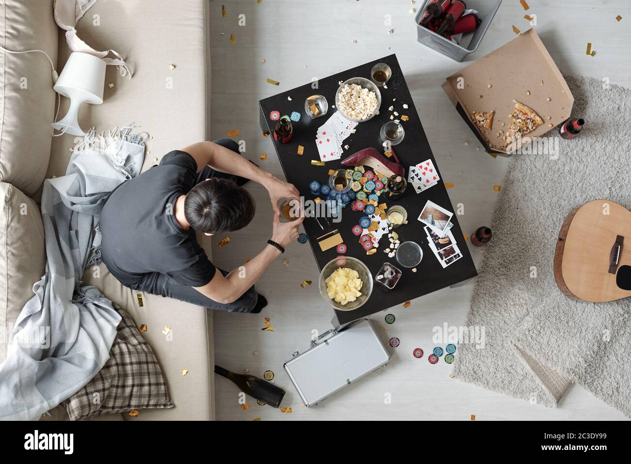 Above view of brunette man sitting on sofa in dirty room with messy ...