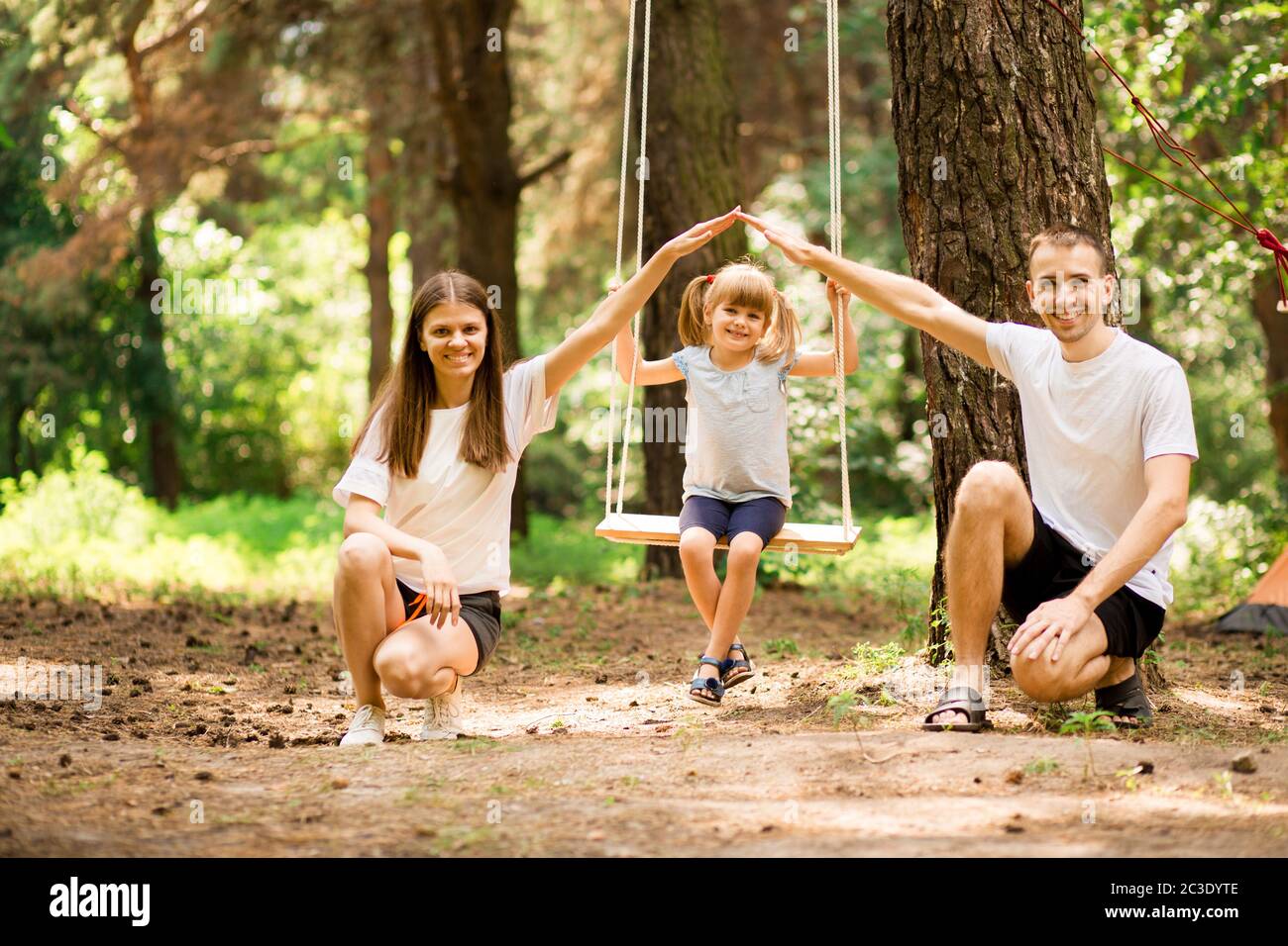 Parents Pushing Children On Swing In Garden. Family with children ...