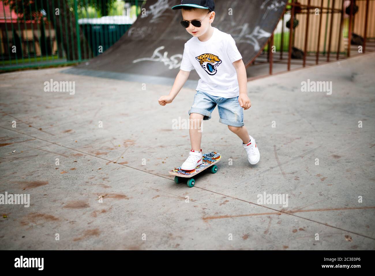 Boy with a skate in a skate park. A boy with glasses learns to skate in ...